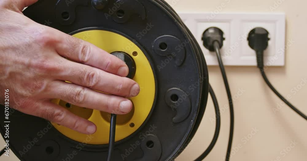 Close-up, a man connects a power cable to a round extension cord. Using ...