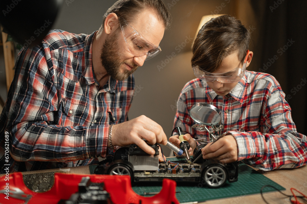 Father teaching his son for soldering and repair remote controlled car ...