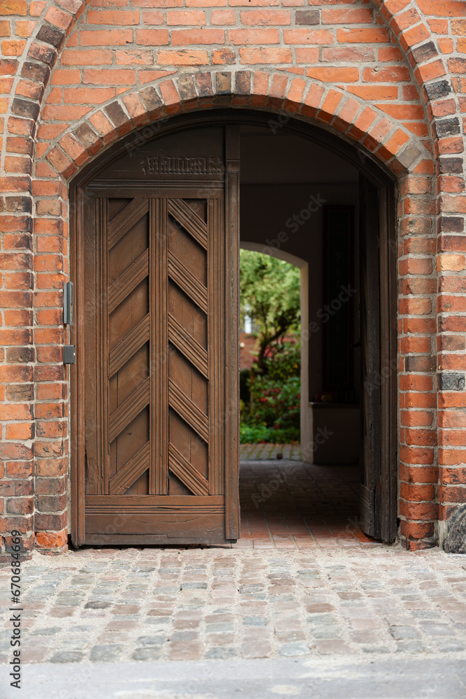 Old chapel arch with red brick, handmade wooden door, and visible green ...