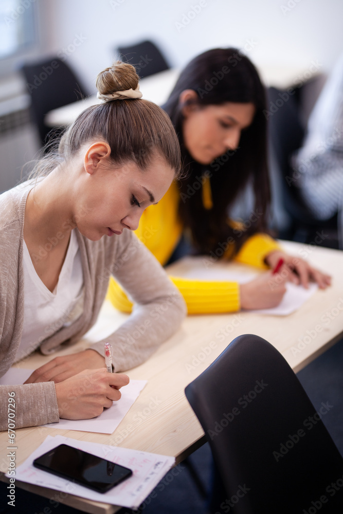 Students taking a test in a classroom. Smart young girls study at a ...