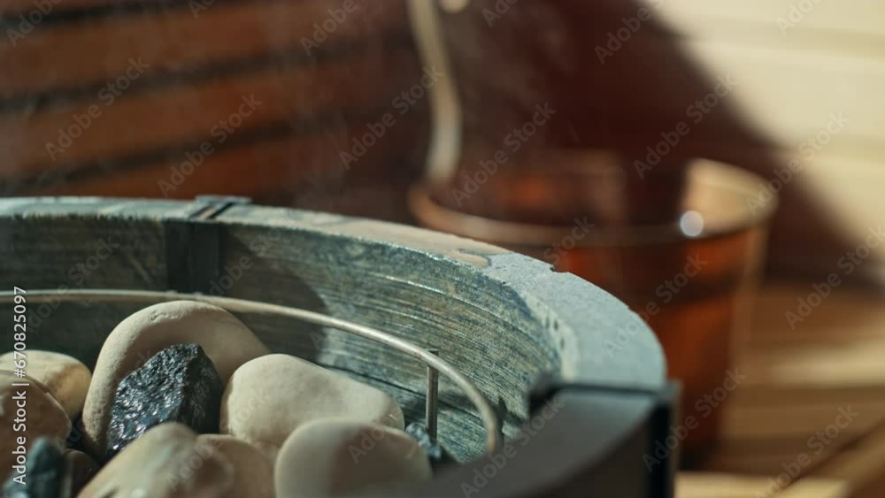 Throwing water on hot sauna stones in sauna stove, using a scoop or ...