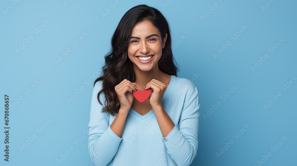 Hispanic woman standing over blue background smiling lovingly and ...