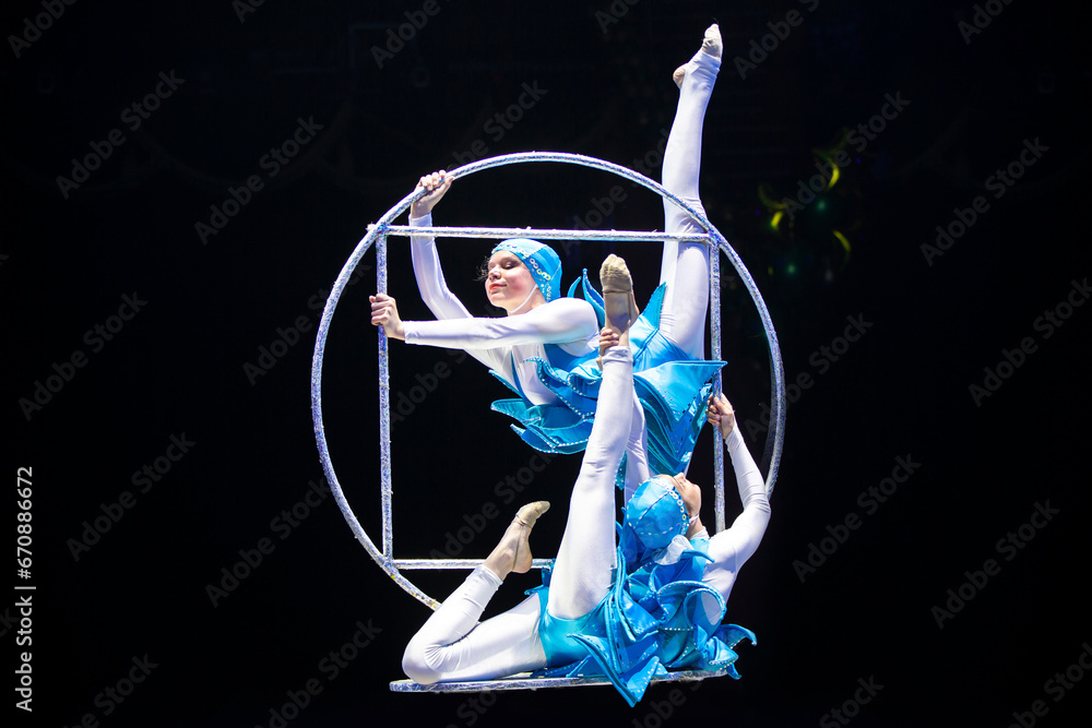 Two acrobat girls show a circus number on a dark background. Acrobatic ...