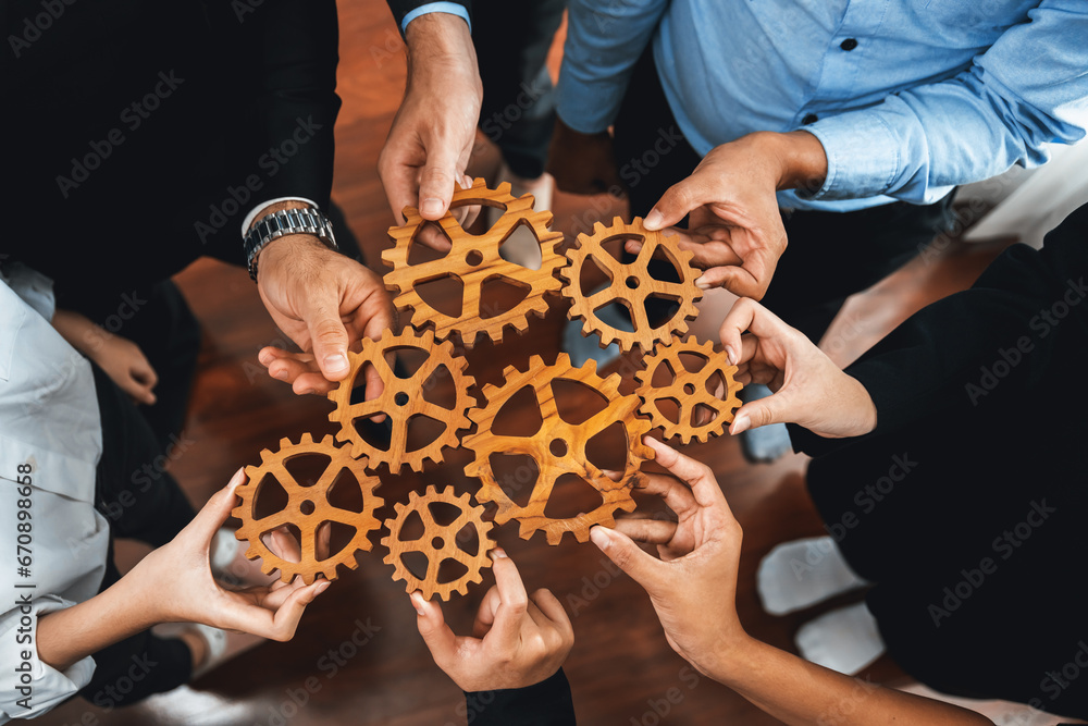 Group of multiracial business people joining gear wheels together as ...