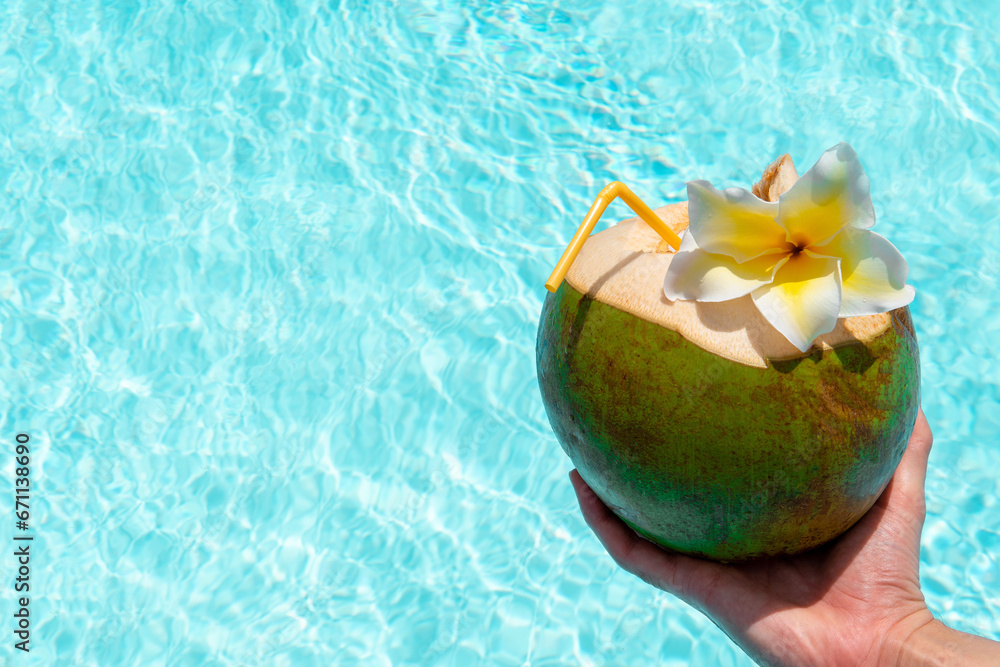Coconut in hand over against swimming pool. Summer vacation at Koh ...