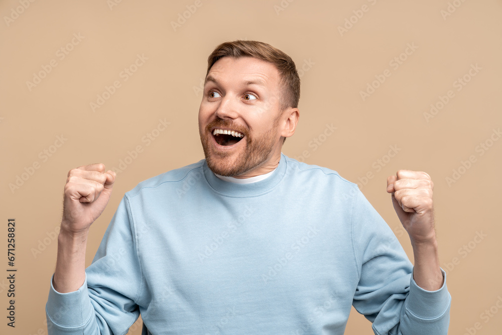 Overjoyed amazed man showing win victory hands gesture clenching fists ...