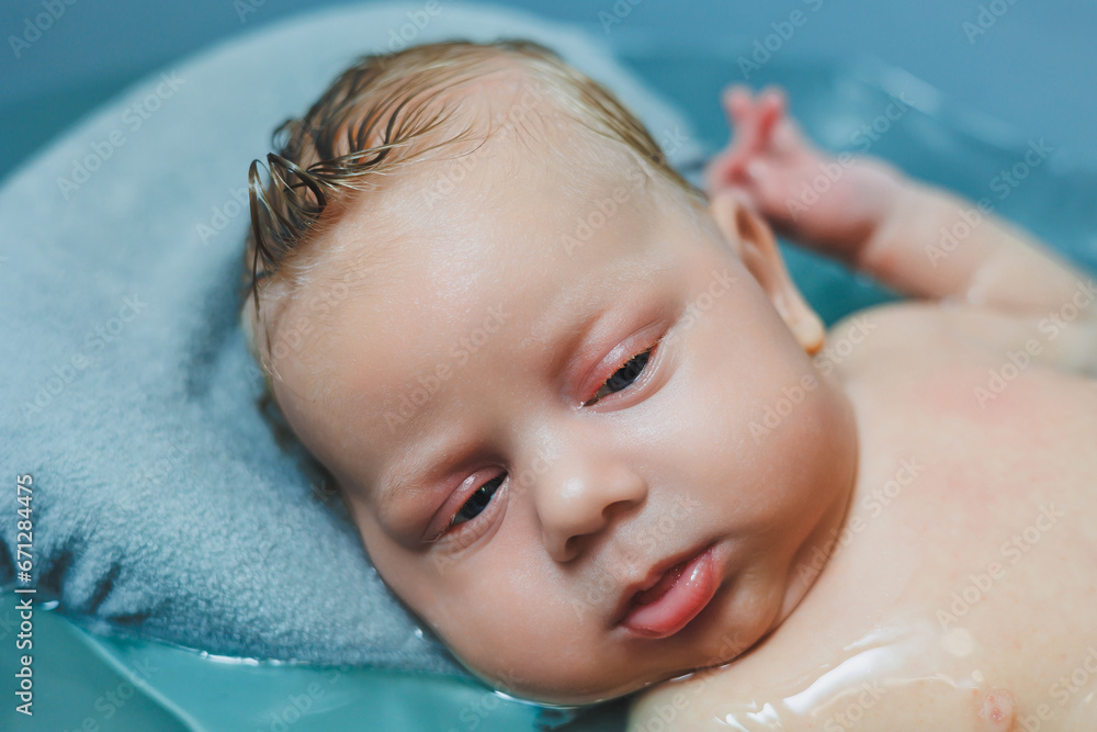 Bathing a baby in a baby bath. The first bath of a newborn baby. A baby ...