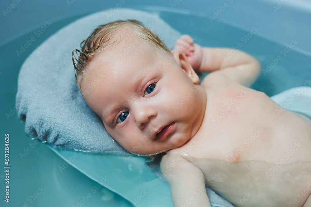 Bathing a baby in a baby bath. The first bath of a newborn baby. A baby ...