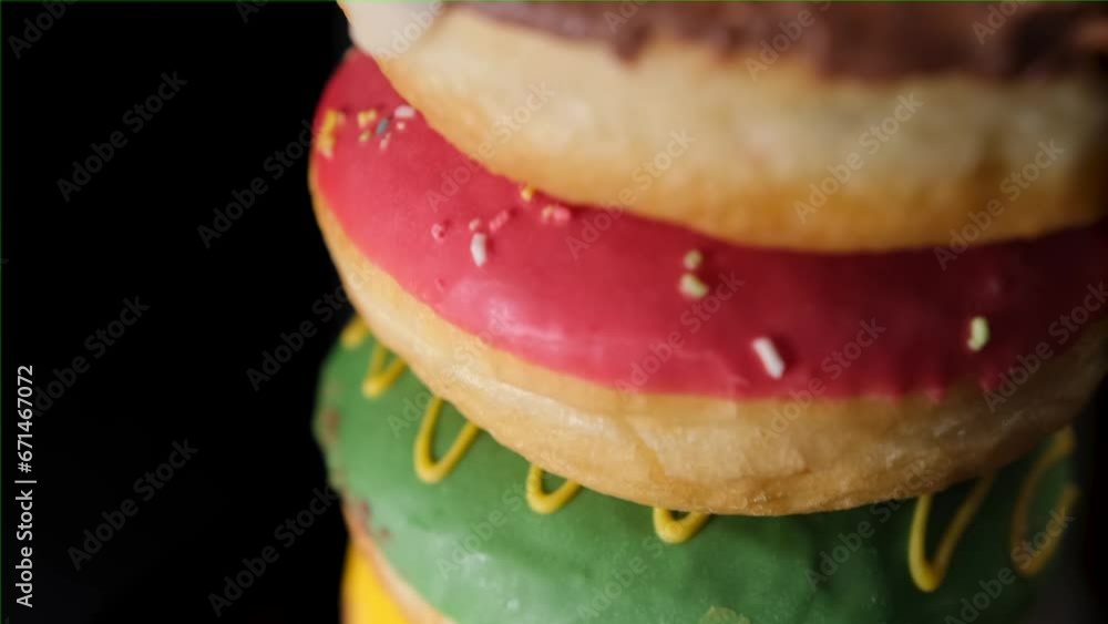 Tall stack of yummy donuts with different color frosting and sprinkles ...
