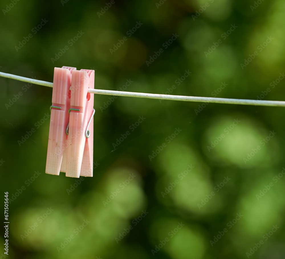 Closeup of washing line with pins hanging outside against a bokeh green ...