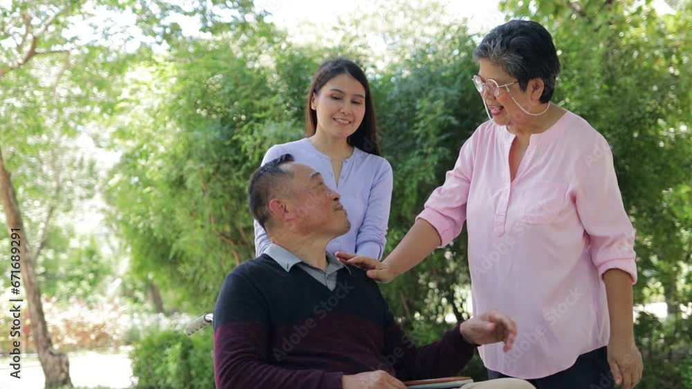 An Asian family relaxes in a park outside. Elderly Asian father in a ...