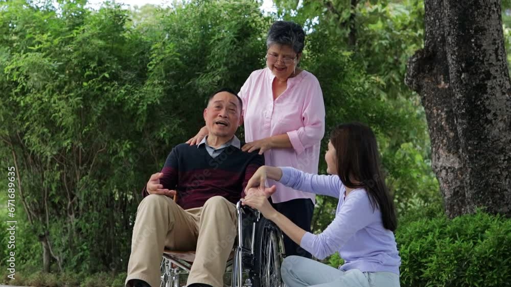An Asian family relaxes in a park outside. Elderly Asian father in a ...