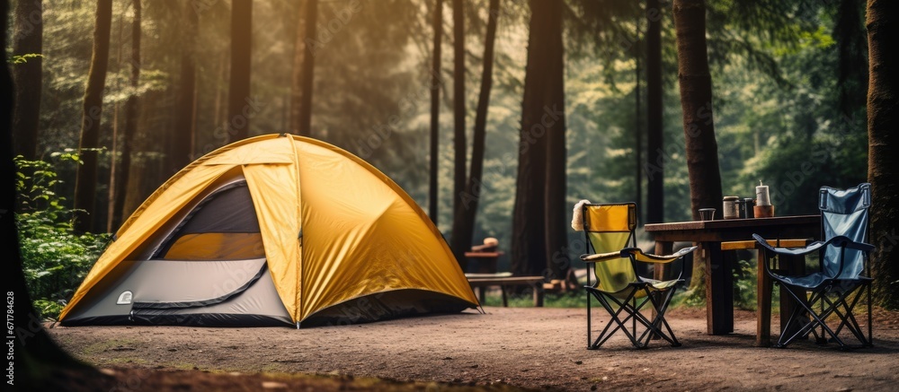 Yellow tent and black chair set up for a camping picnic in a forest ...