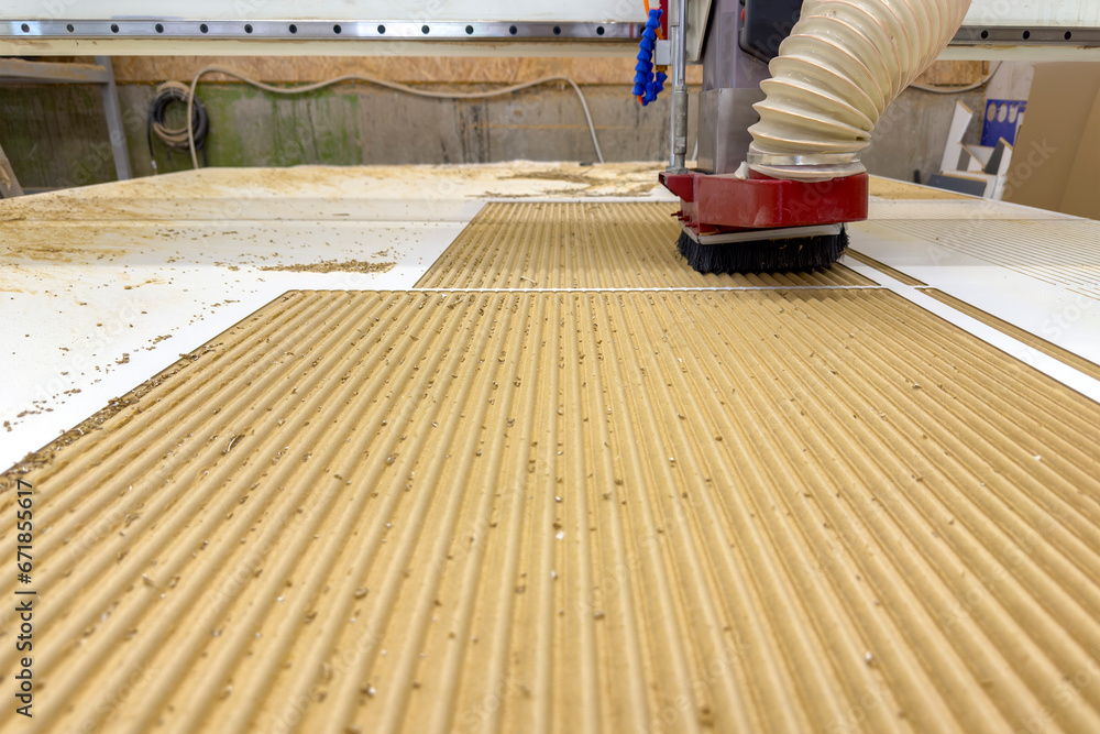 Furniture production process. A CNC machine mills wood elements for ...