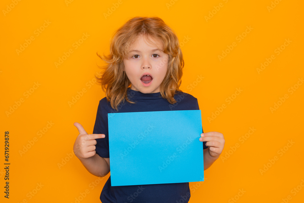 Excited kid boy showing empty sheet of paper, isolated on yellow ...