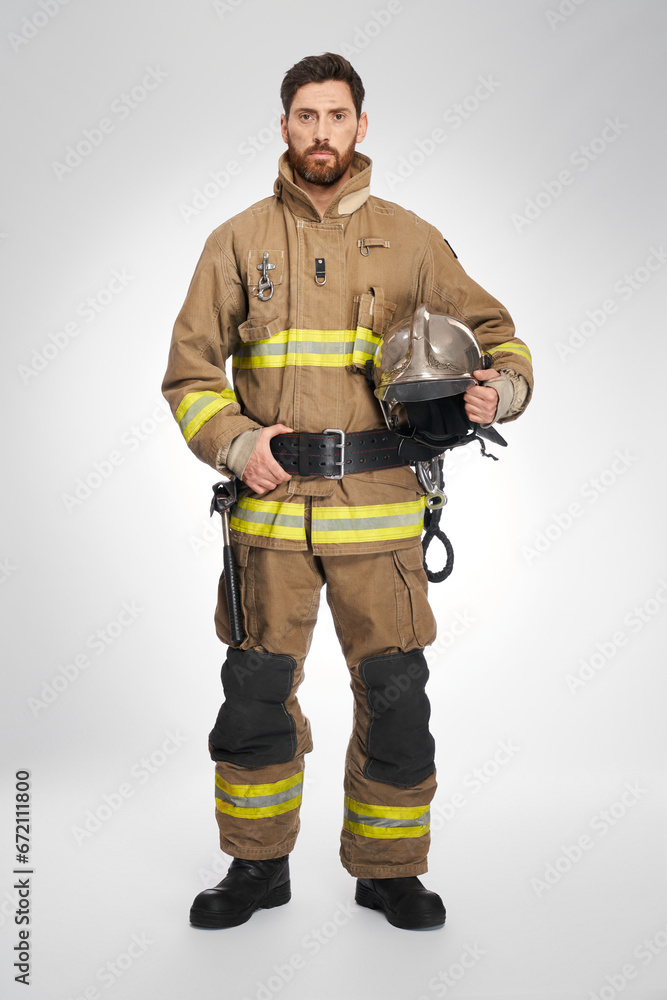 Serious handsome caucasian firefighter in full gear looking at camera ...