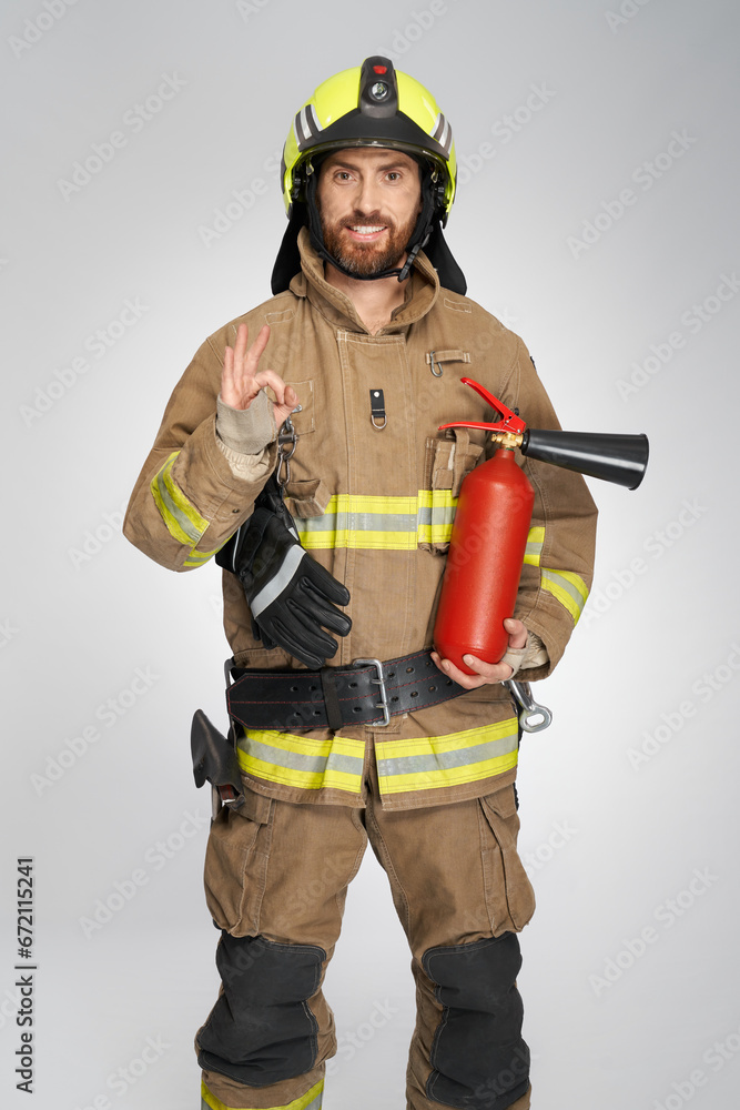 Happy firefighter with extinguisher showing okay sign indoors. Front ...