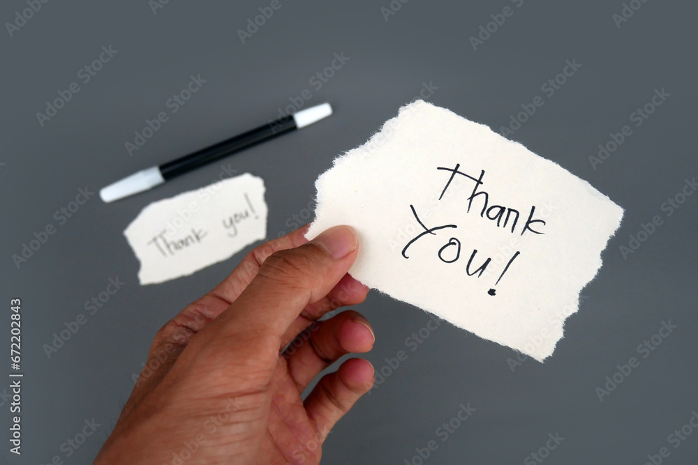 Hand-holding paper with the words 'Thank you!' handwritten on a torn ...