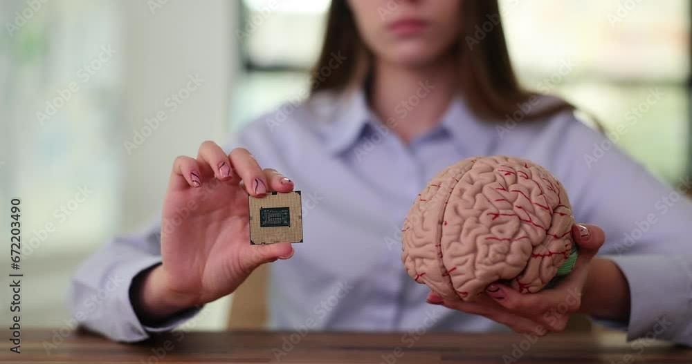 Female holds artificial model of brain and computer motherboard in lit ...