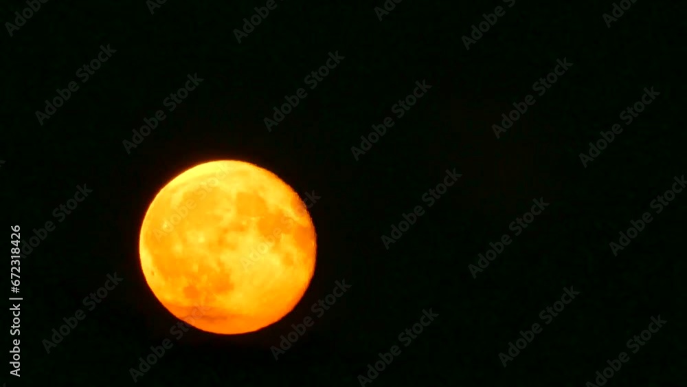 Dark night sky and orange and yellow rising moon disc with Atmospheric ...