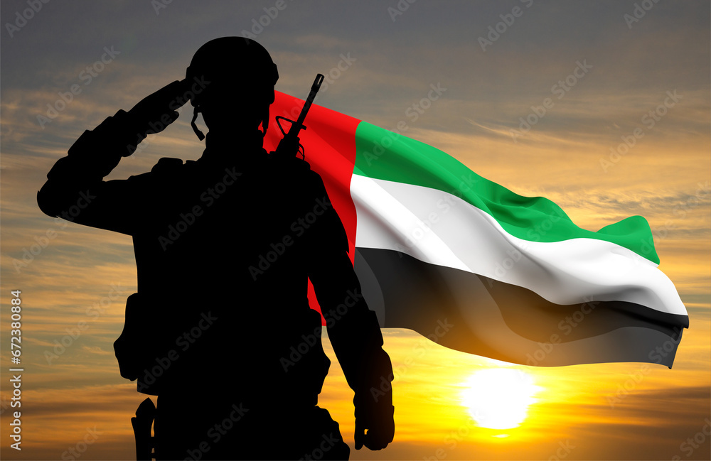 Silhouette of a saluting soldier with the flag of UAE against the ...
