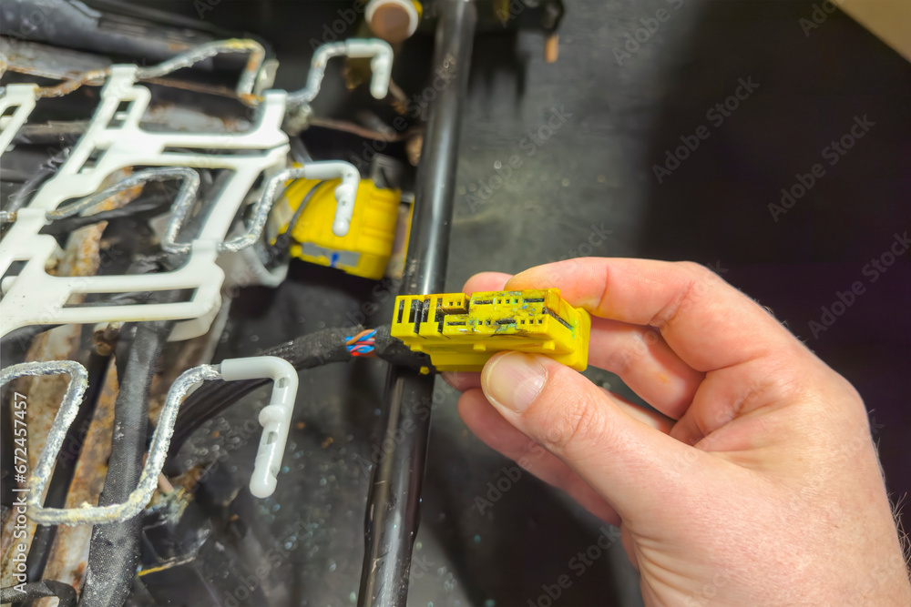 Repairing automotive electrical wiring. An auto electrician holds a ...