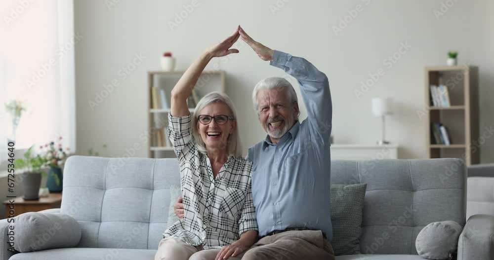 Serious mature elder husband and wife joining hands overhead, showing ...