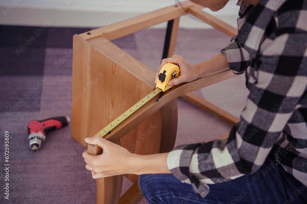 Women measuring length of chair with measure tape while assembling and ...