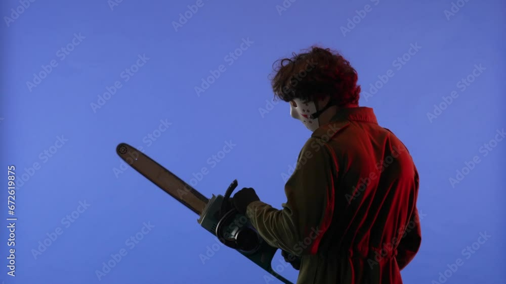 Man in white mask with chainsaw in hands on blue background with red ...