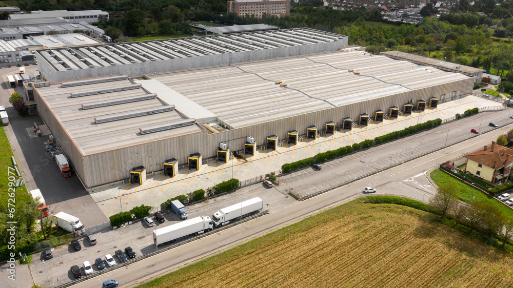 Aerial view of a warehouse and its roof. In the parking lot some trucks ...