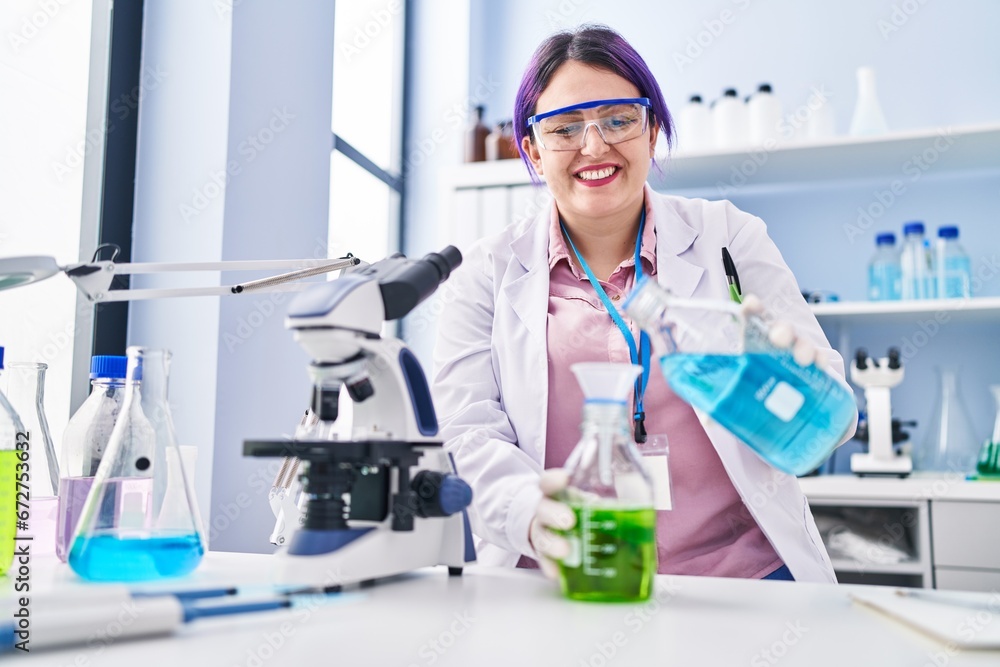 Young beautiful plus size woman scientist pouring liquid on test tube ...
