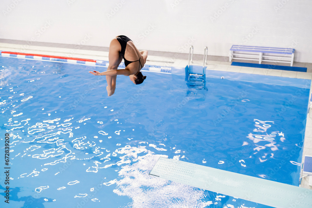 girl doing extreme tricks jumping into water, spring-board diving ...