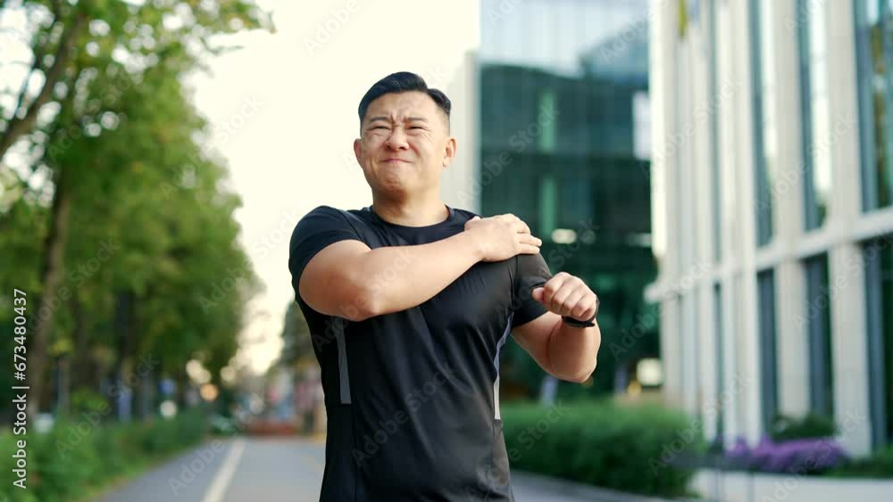 Upset asian athletic man experiencing acute shoulder pain during ...