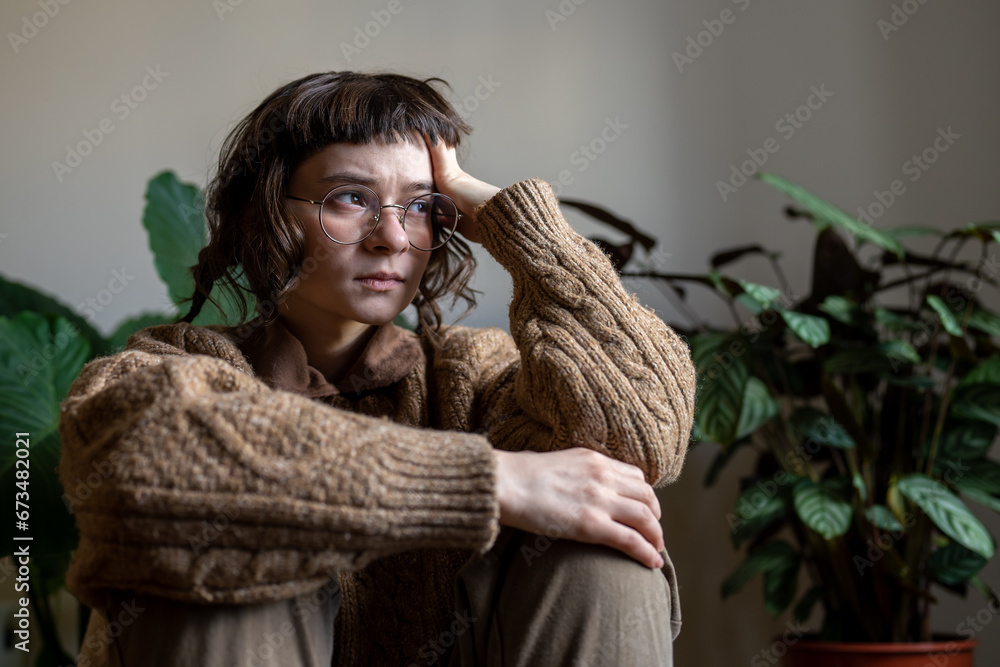 Lonely stressed teenager sitting at home alone looking at window ...
