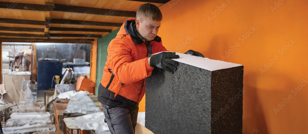 Foto de Man in orange jacket installing insulation, lays graphite ...