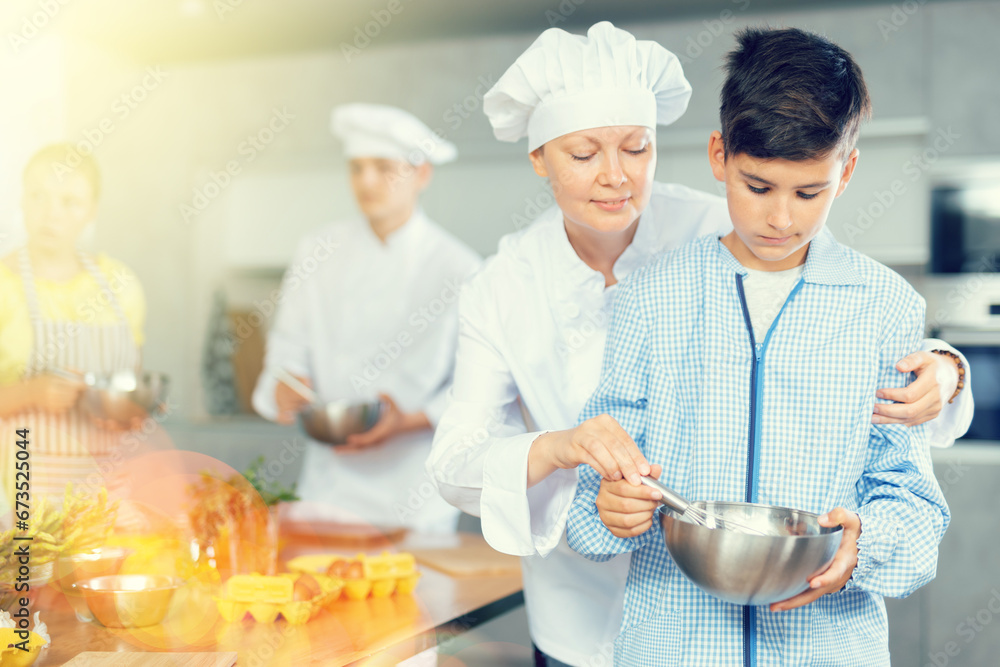 In restaurant kitchen during children cooking class, female chef help ...