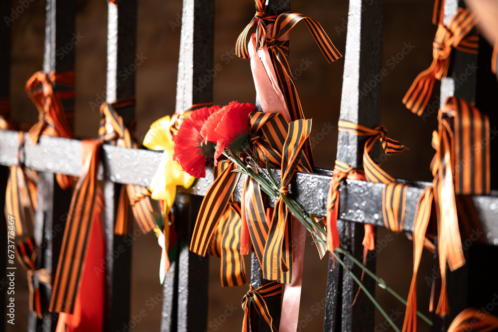 Many St. George ribbons are tied to the black metal structure as a ...