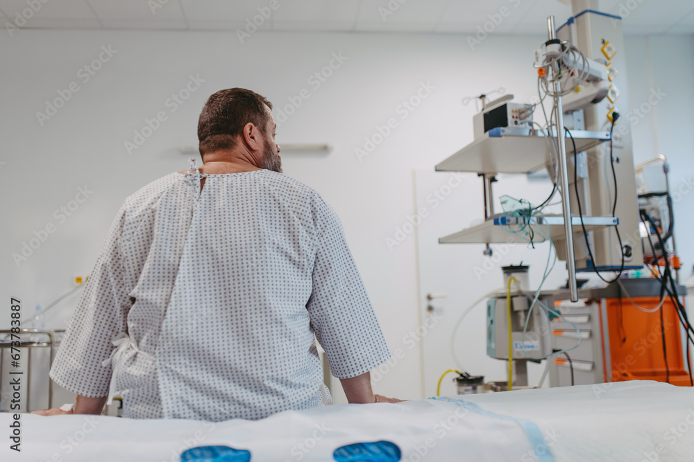 Rear view of overweight patient in hospital gown waiting for medical ...