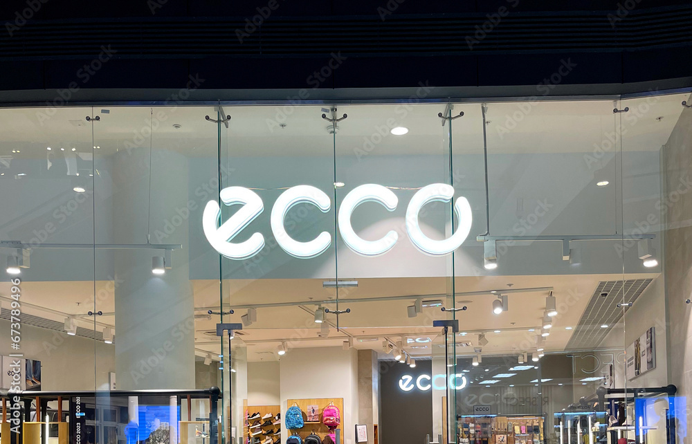 Large bright white Ecco logo close-up above entrance to official store. Famous shoe brand ...