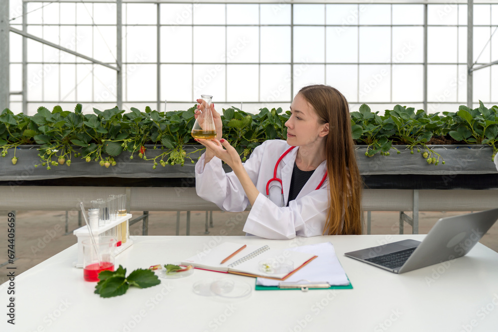 Caucasian female botanical scientist in white gown observes yellow ...