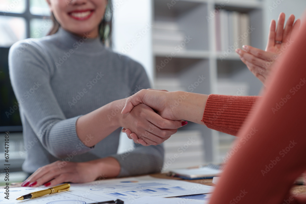 Two businesswomen office workers shaking hands Clap your hands at success Working together as a ...