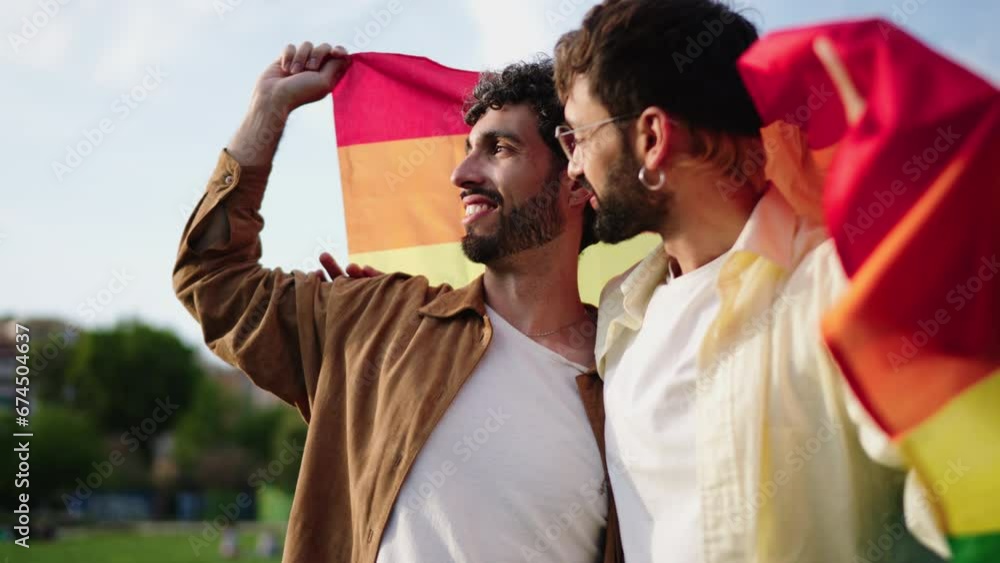 Gay couple joyously holding up pride flag, their faces alight with ...