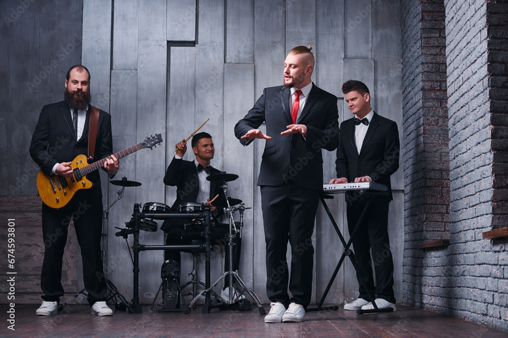 Music band and fashion. Handsome young men in suits playing rock and ...