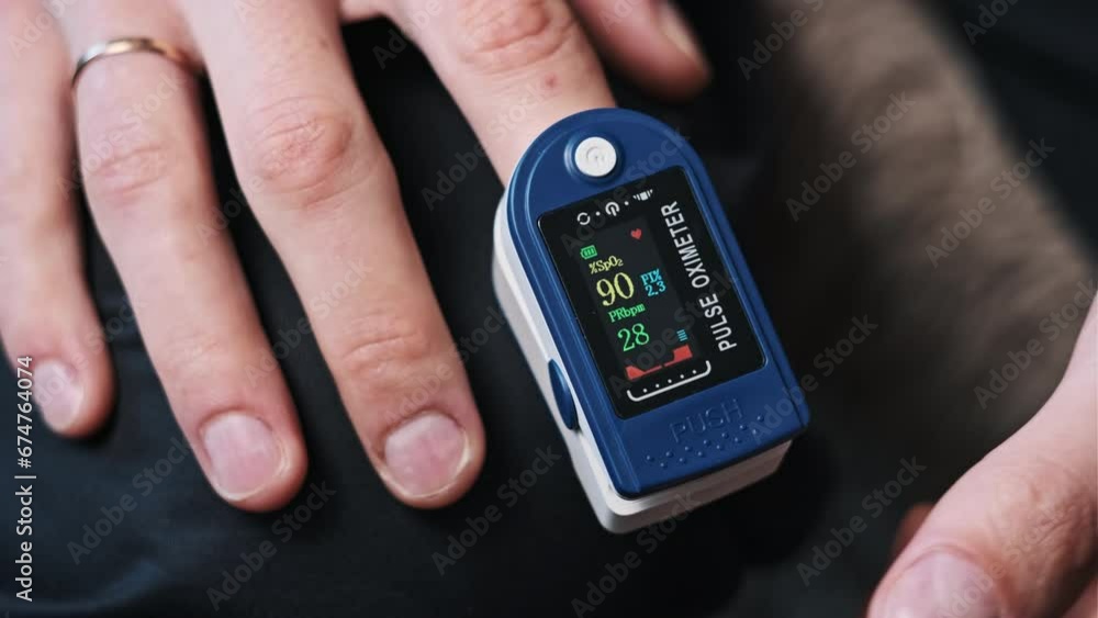Man measures pulse and oxygen saturation with a pulse oximeter at home ...