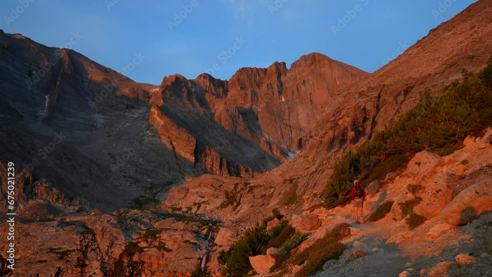 Vidéo Stock Cinematic first light sunrise orange red hiker Longs Peak ...