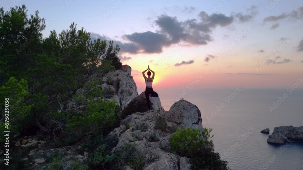 Dramatic aerial top view flight Ibiza cliff Yoga tree pose model girl ...