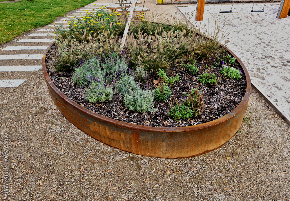 the oval ellipse of the flower bed is lined with a rusty sheet metal ...
