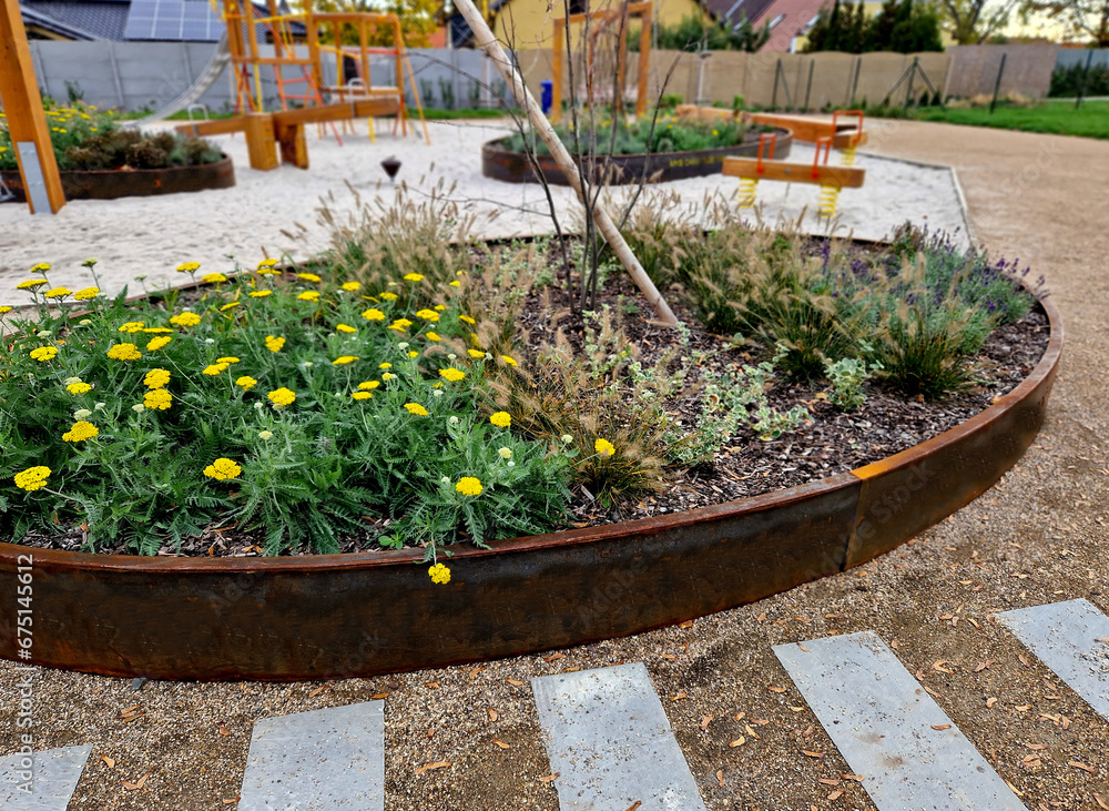the oval ellipse of the flower bed is lined with a rusty sheet metal ...