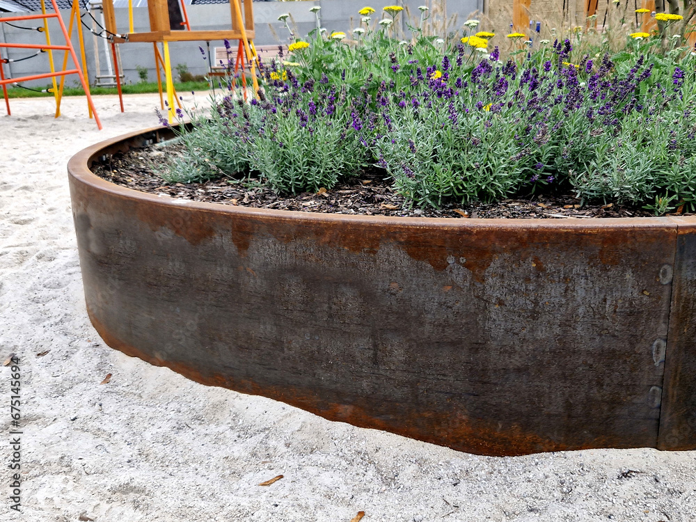 the oval ellipse of the flower bed is lined with a rusty sheet metal ...