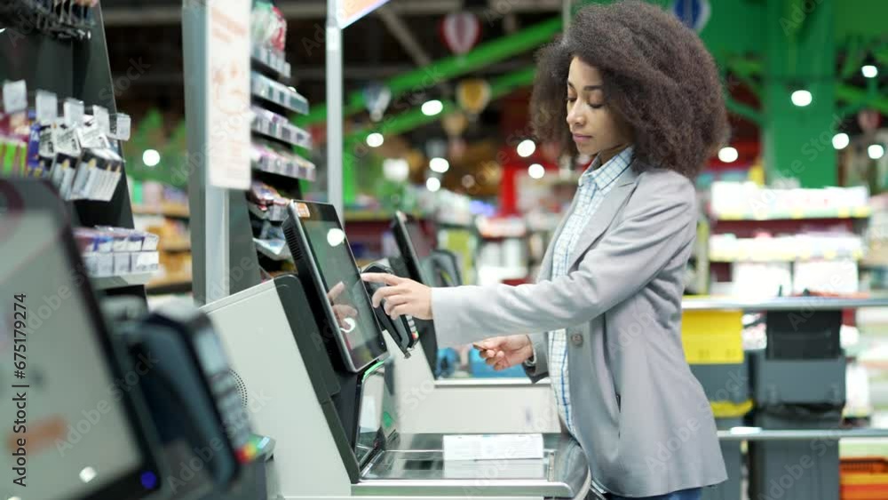 Female shopper using a self-service cashier checkout in a supermarket ...